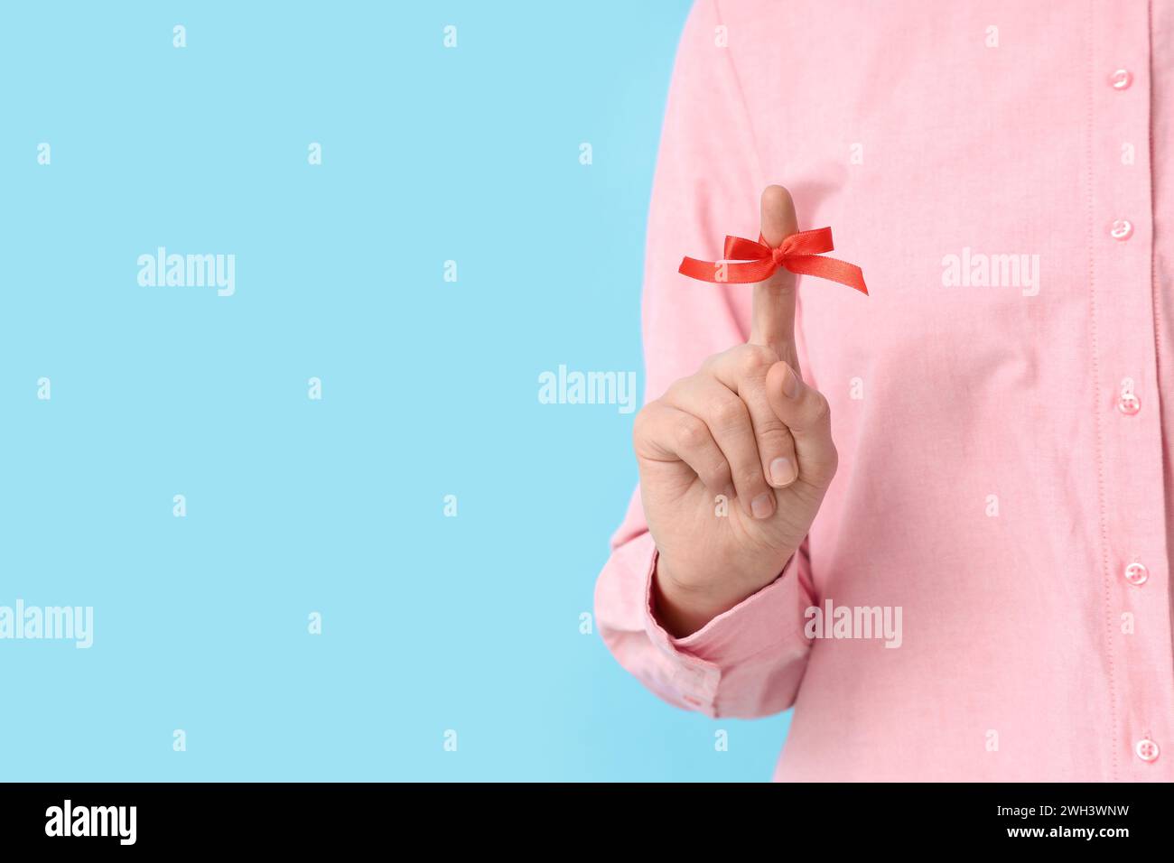 Woman with red bow on index finger against blue background. Reminder ...