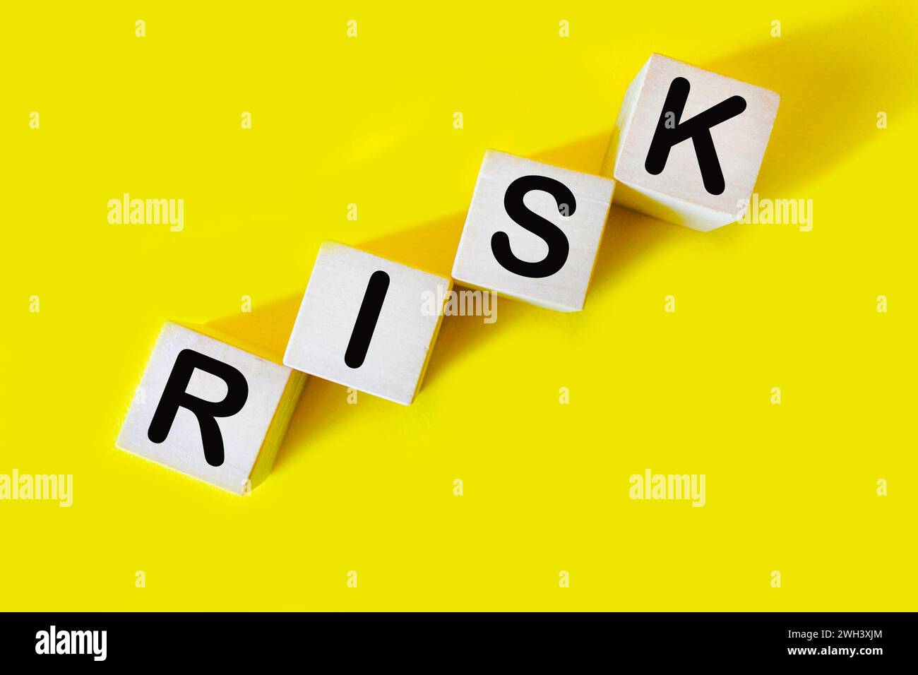 The word RISK. Wooden letter cubes isolated on a yellow background with ...