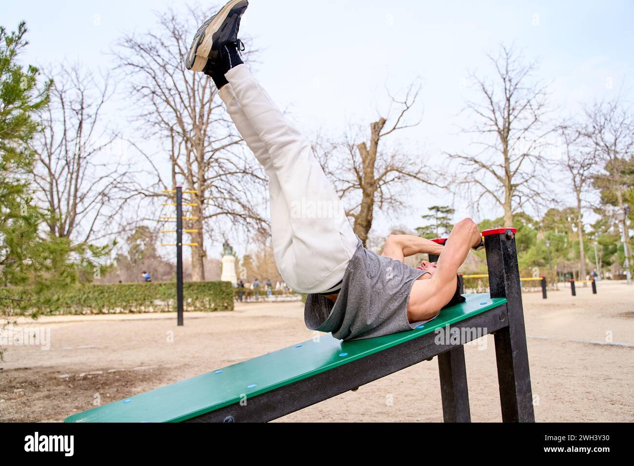 young male athlete doing sit-ups by lifting his legs in an outdoor ...
