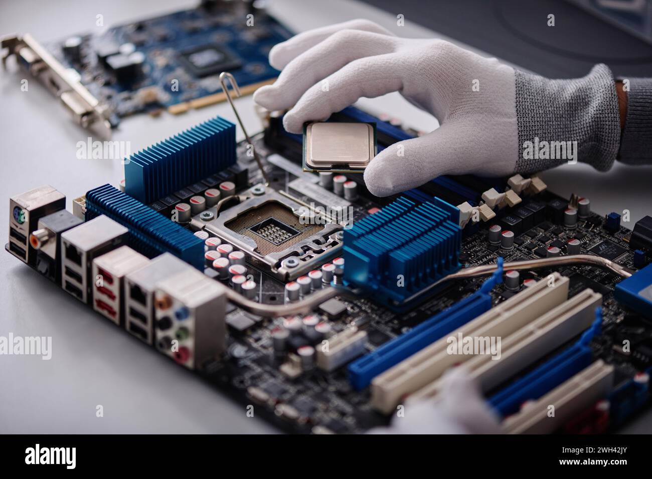 Hand of unrecognizable repairman inserting CPU into motherboard socket ...