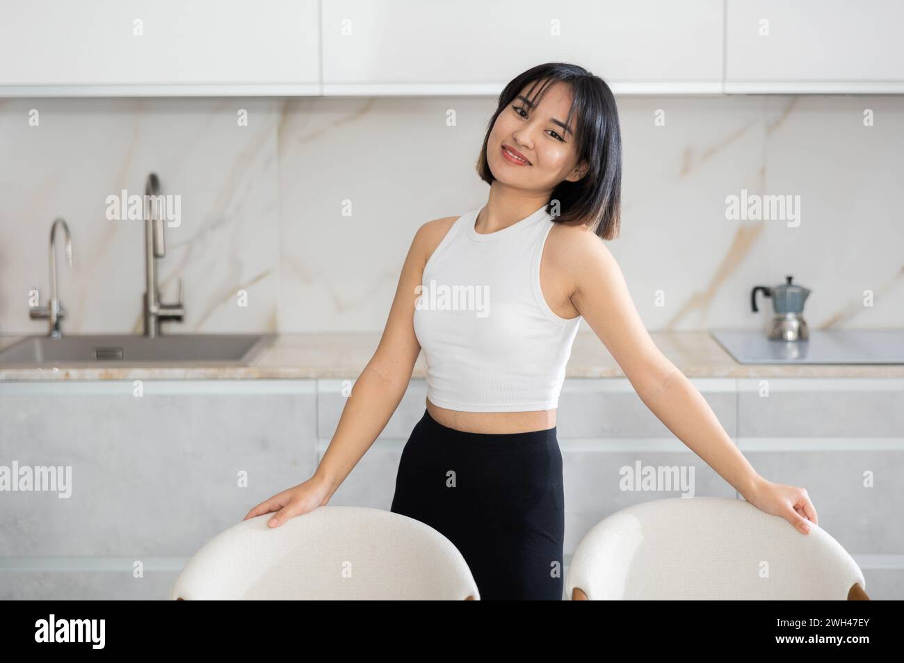 Smiling young Asian girl standing at table in the kitchen Stock Photo ...