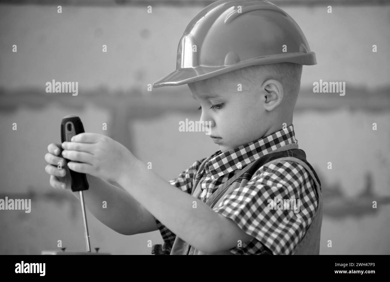 Kid boy twists bolt with screwdriver. Child repairman with repair tool ...