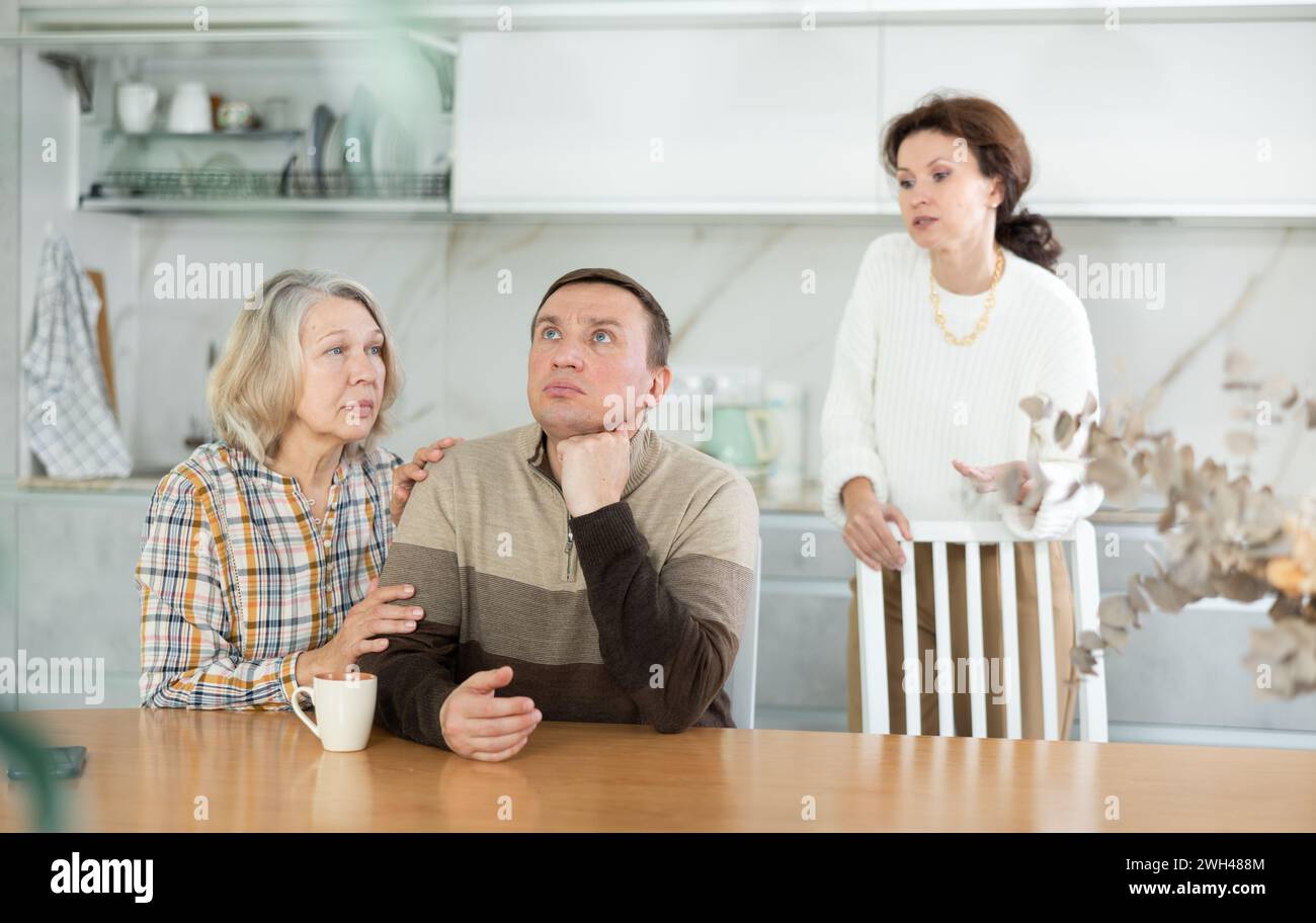 Family members quarreling in the kitchen and old woman trying to calm ...