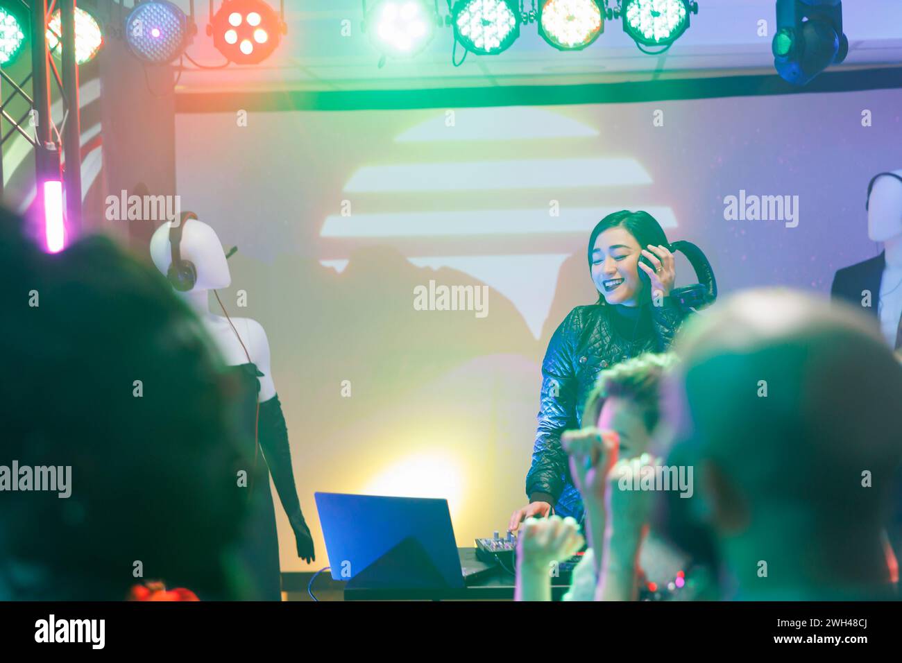 Dj mixing electronic music on stage with spotlights at discotheque ...