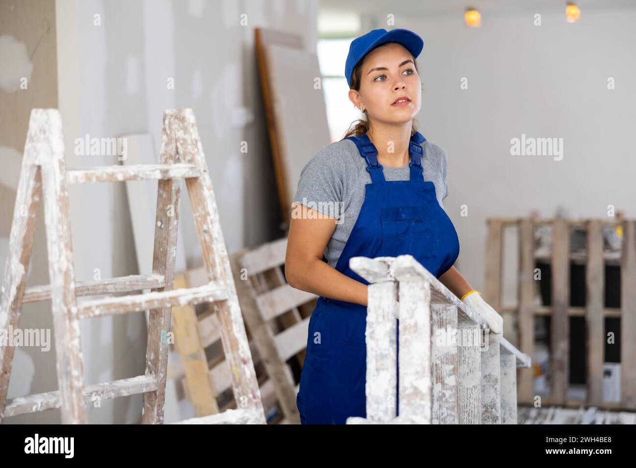 Female construction worker carrying ladder during renovation works ...