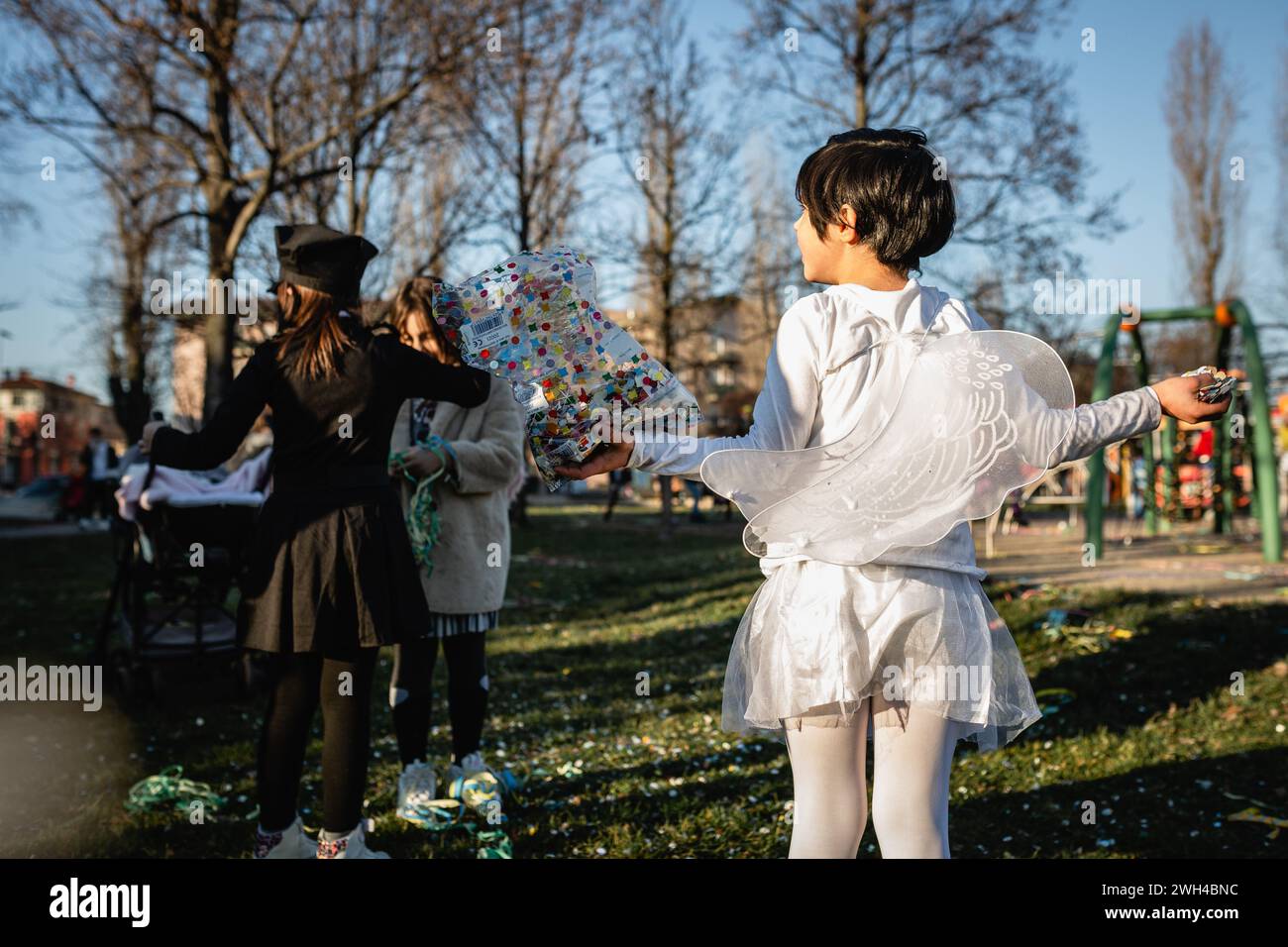 rear view of standing girl in angel carnival costume with wings on the ...
