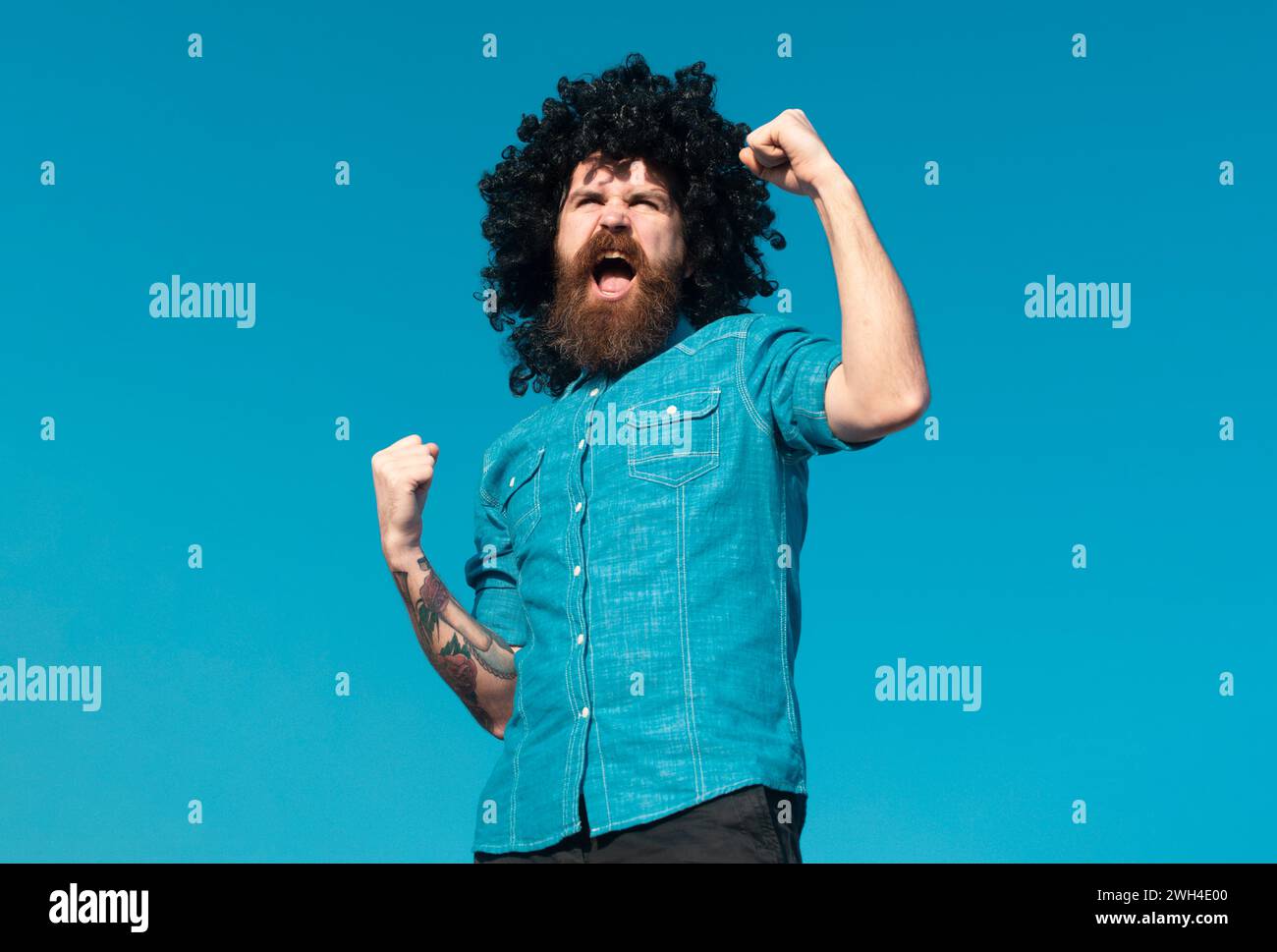 Funny nerdy guy. Crazy funny bearded man with wig on sky background ...