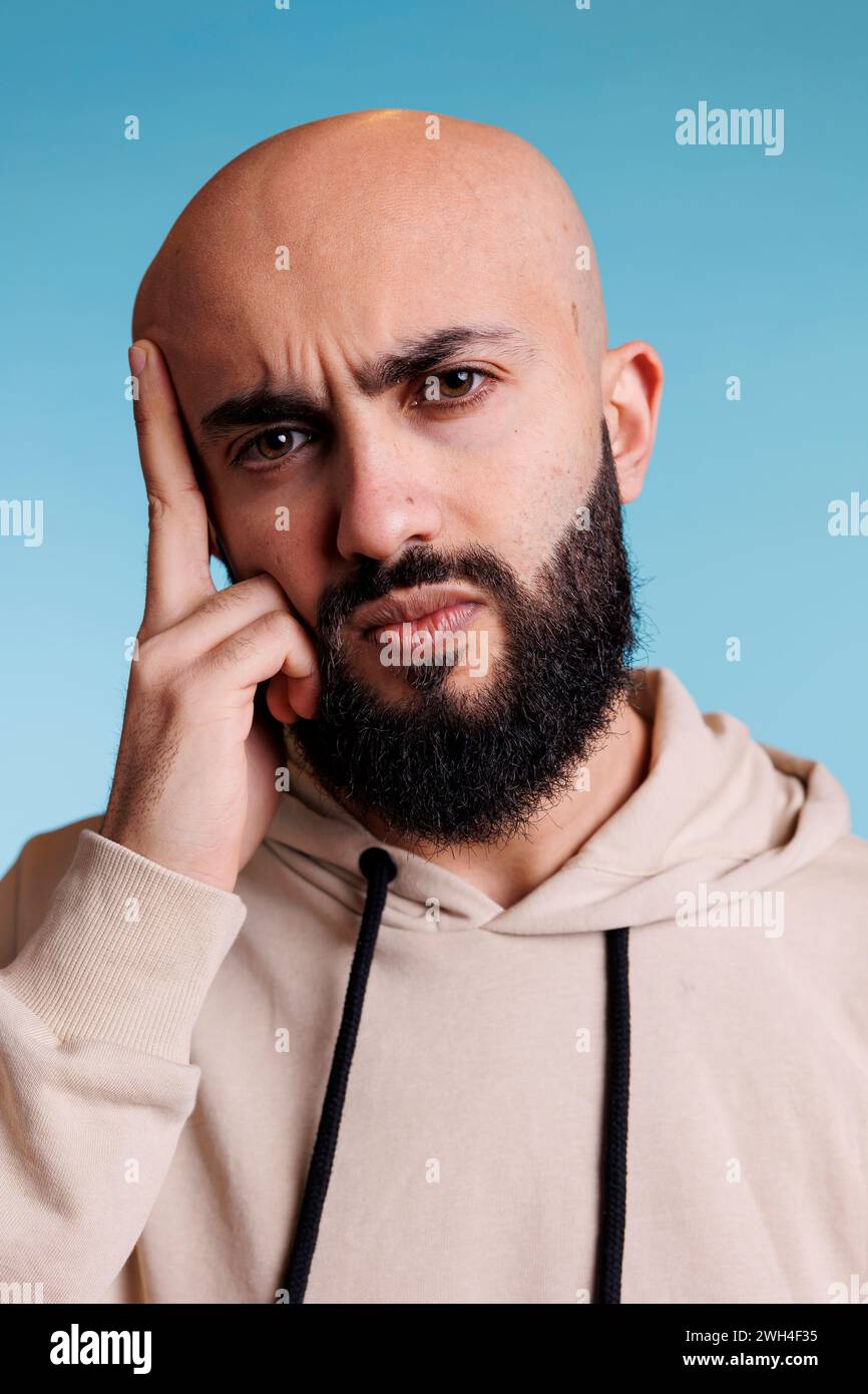 Arab man grimacing in pain while having migraine and holding head with ...