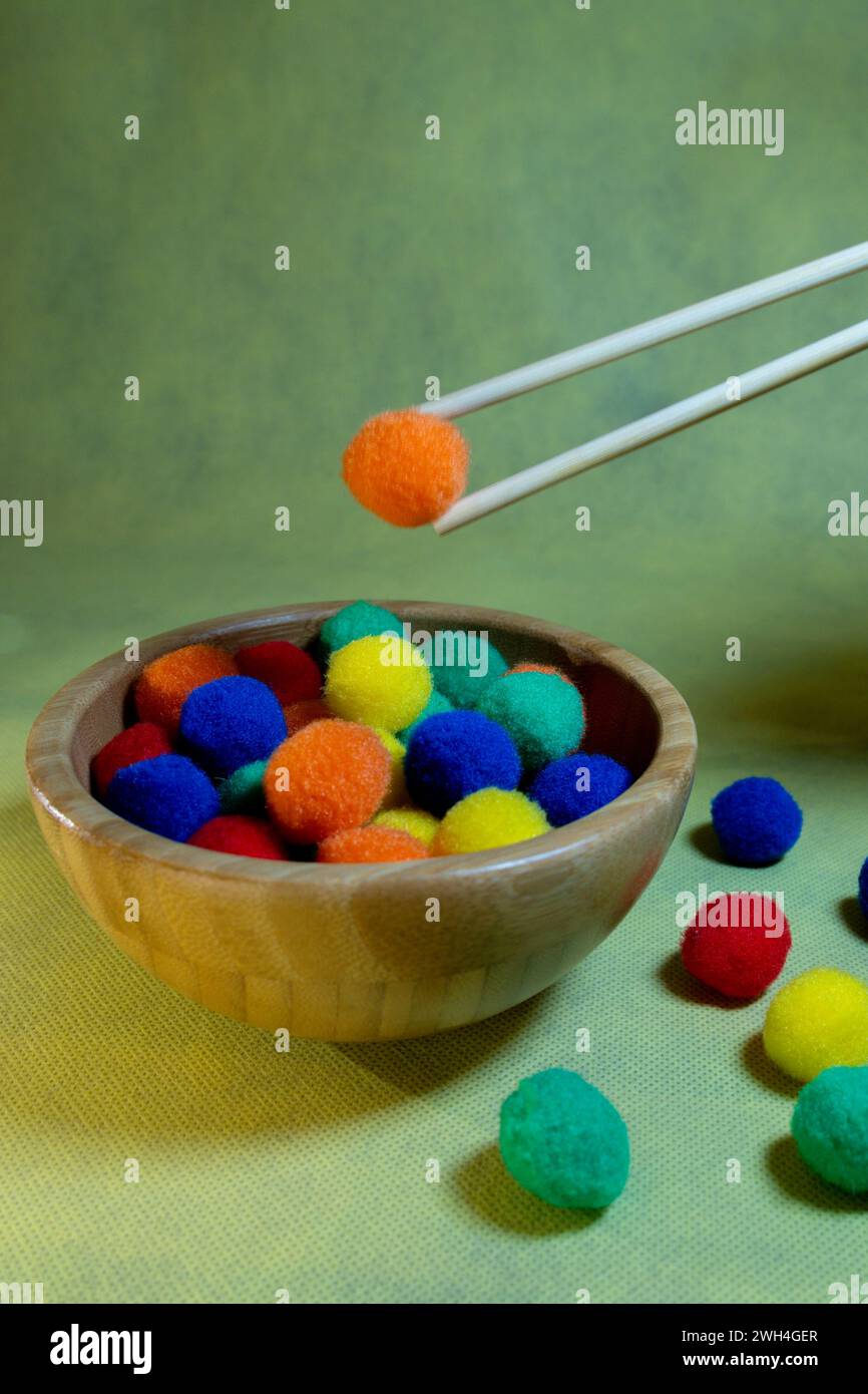 person learning how to use chopsticks to eat and practicing with a ...