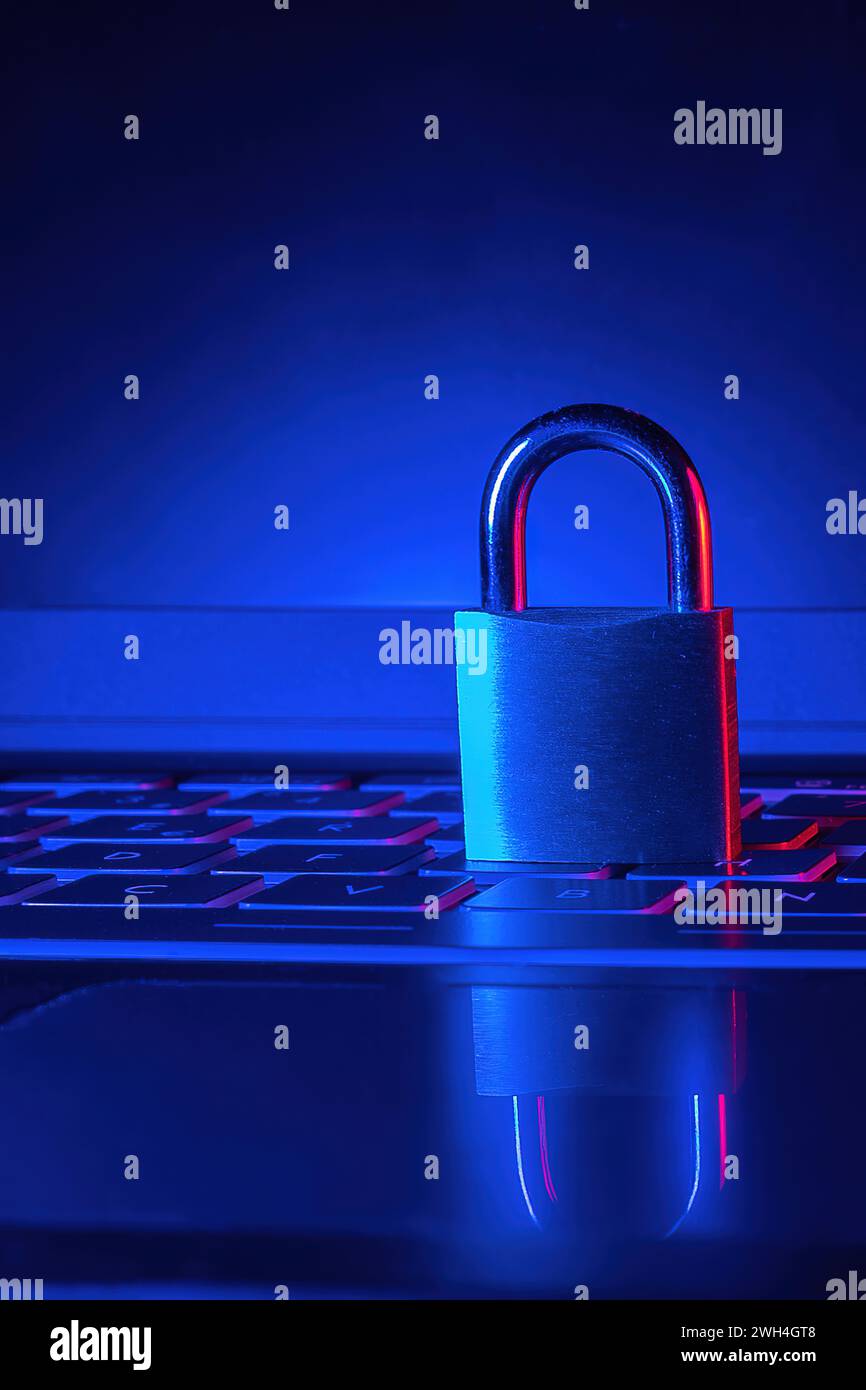 vertical photo of a closed padlock and a computer keyboard with blue ...