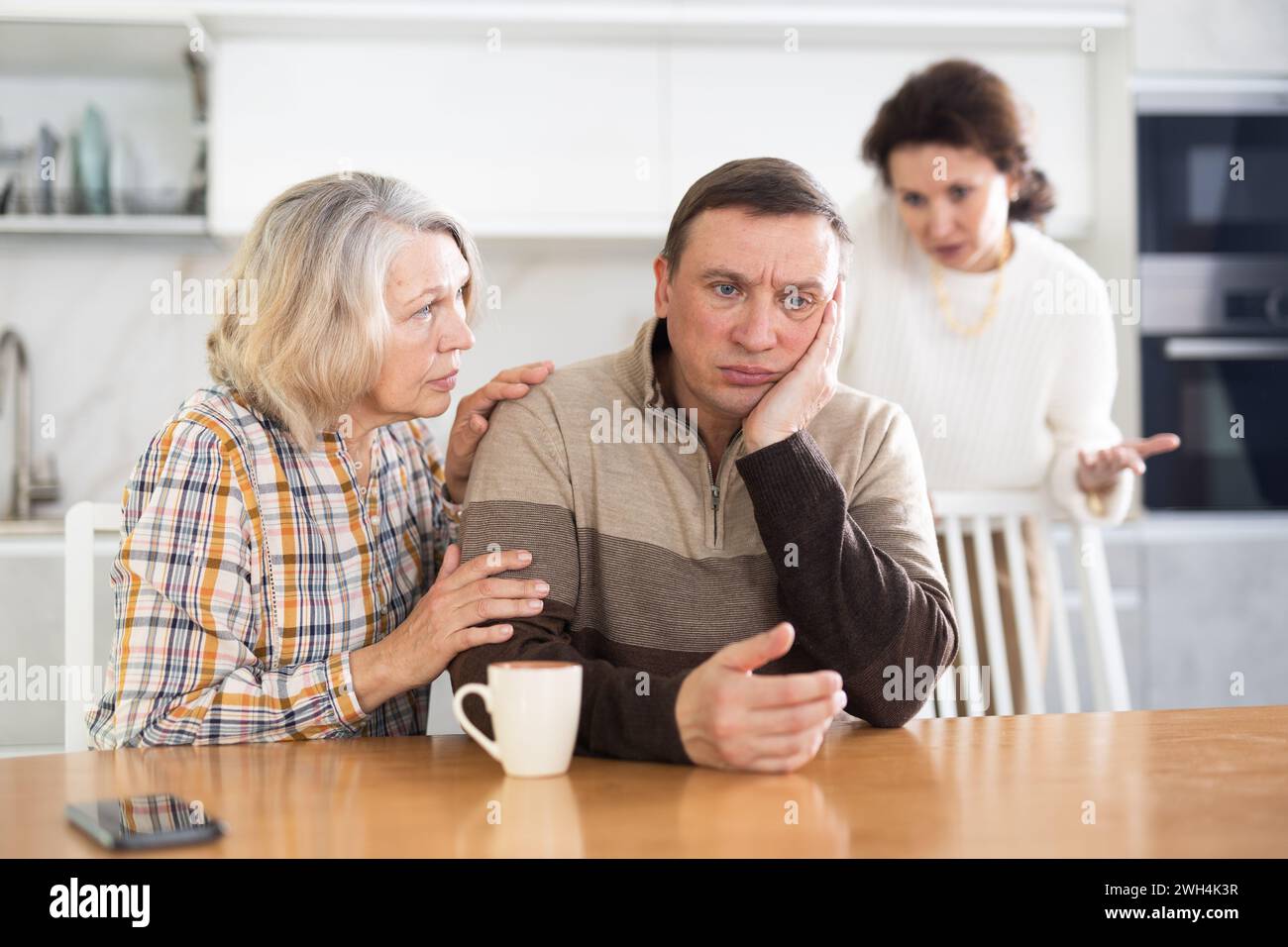 Family members quarreling in the kitchen and old woman trying to calm ...