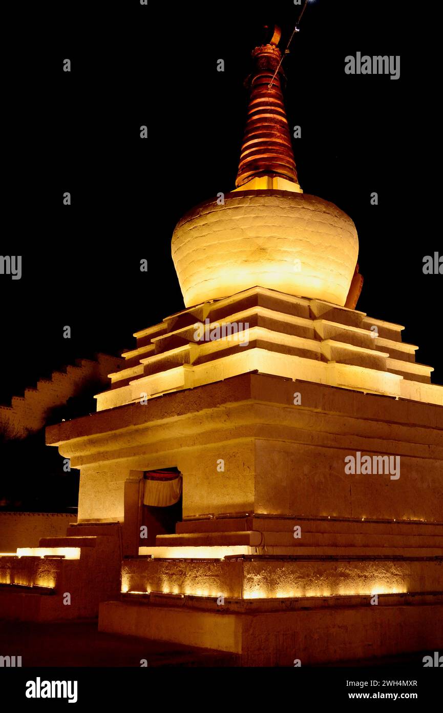 An illuminated stupa, also known as a chorten, lights up the night sky ...