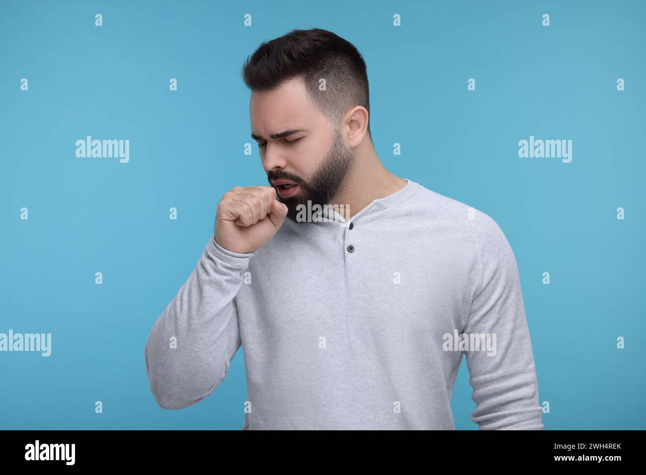 Sick man coughing on light blue background Stock Photo - Alamy