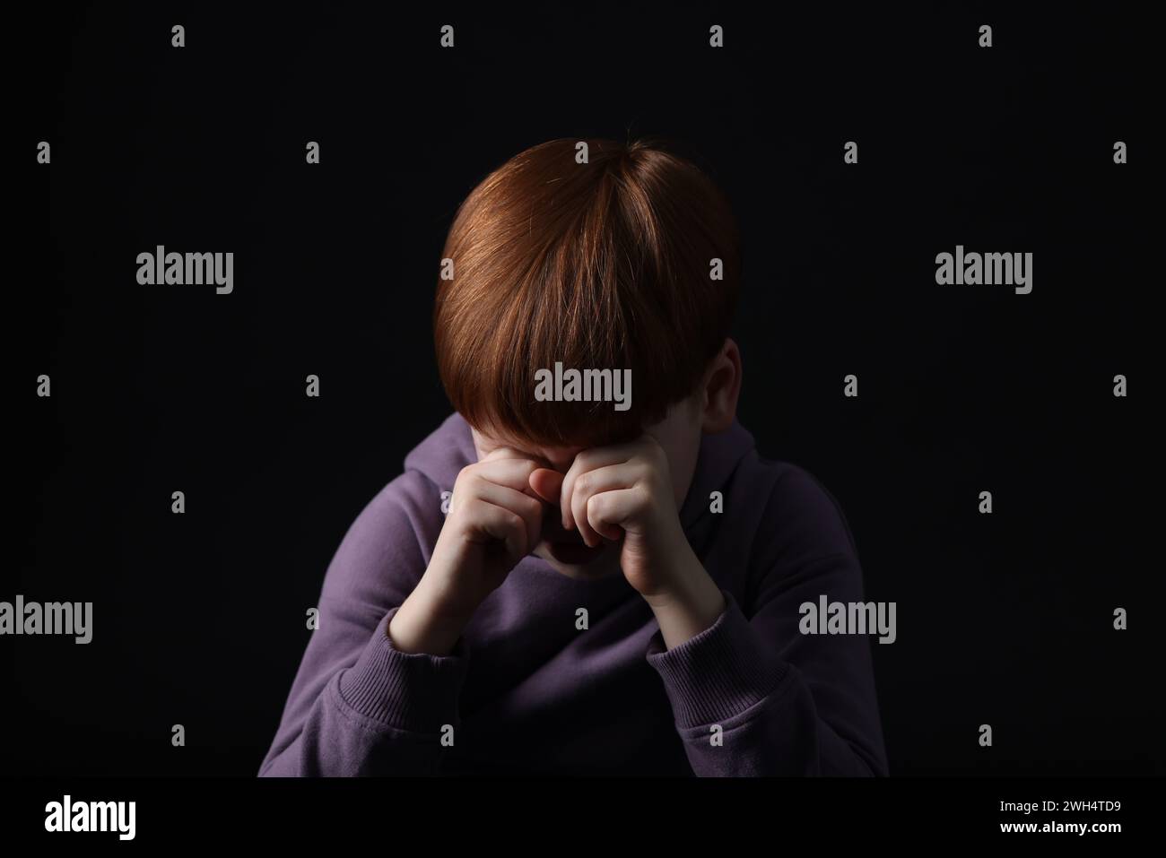 Sad little boy crying on black background Stock Photo - Alamy