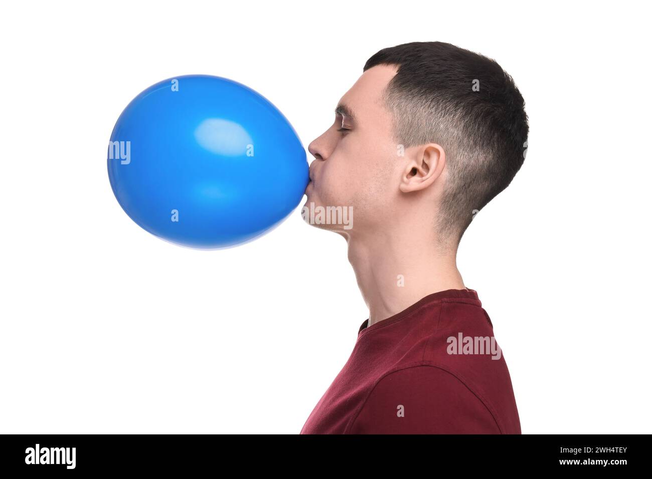 Young man inflating light blue balloon on white background Stock Photo ...