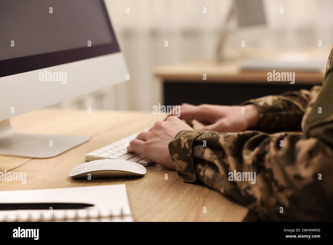 Military service. Soldier working with computer at wooden table in ...