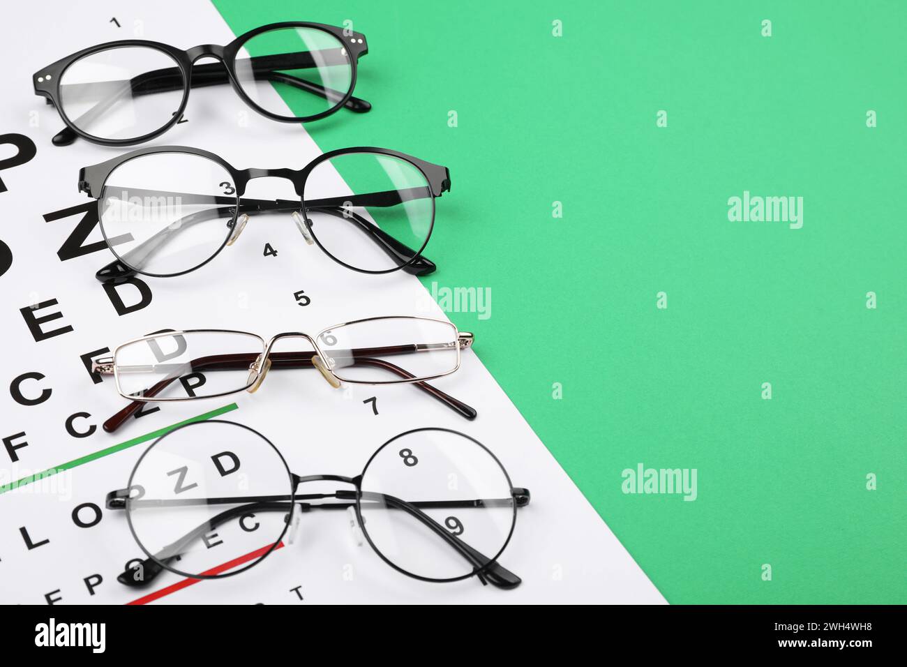 Vision test chart and glasses on green background, closeup. Space for ...