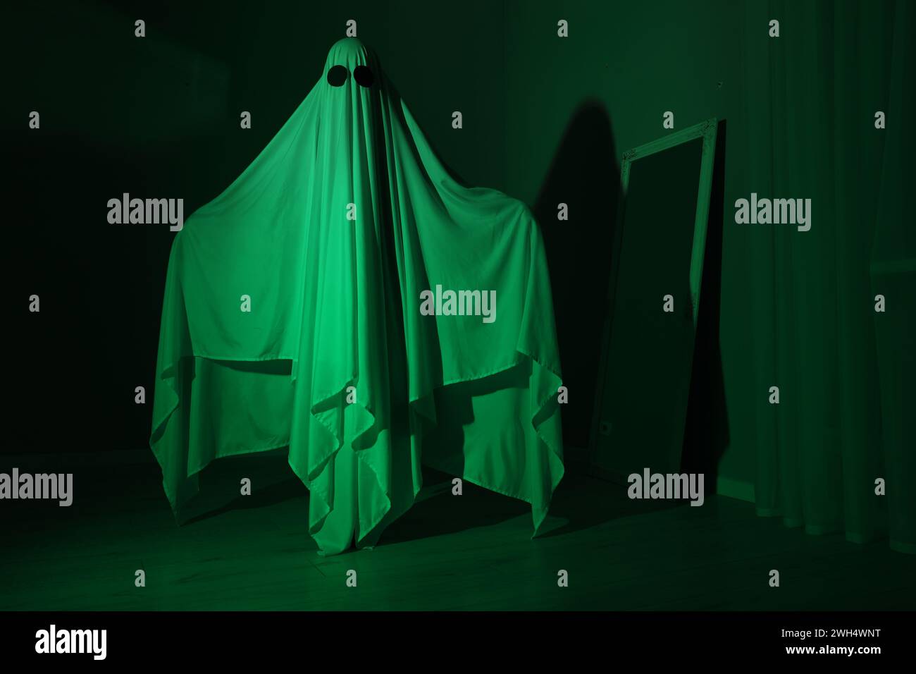 Creepy ghost. Woman covered with sheet in green light Stock Photo - Alamy