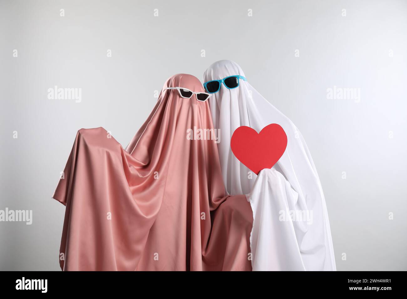 Cute ghosts. Couple in color sheets and sunglasses with red heart on ...