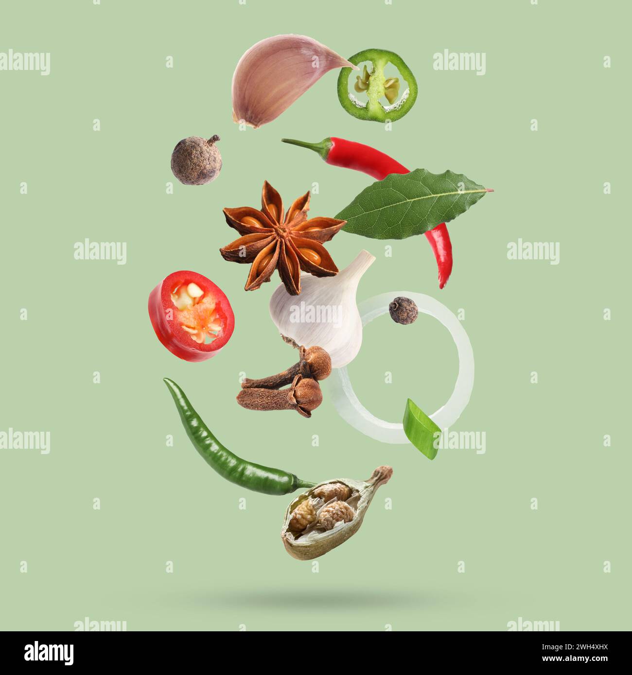 Different spices falling on light green background Stock Photo - Alamy