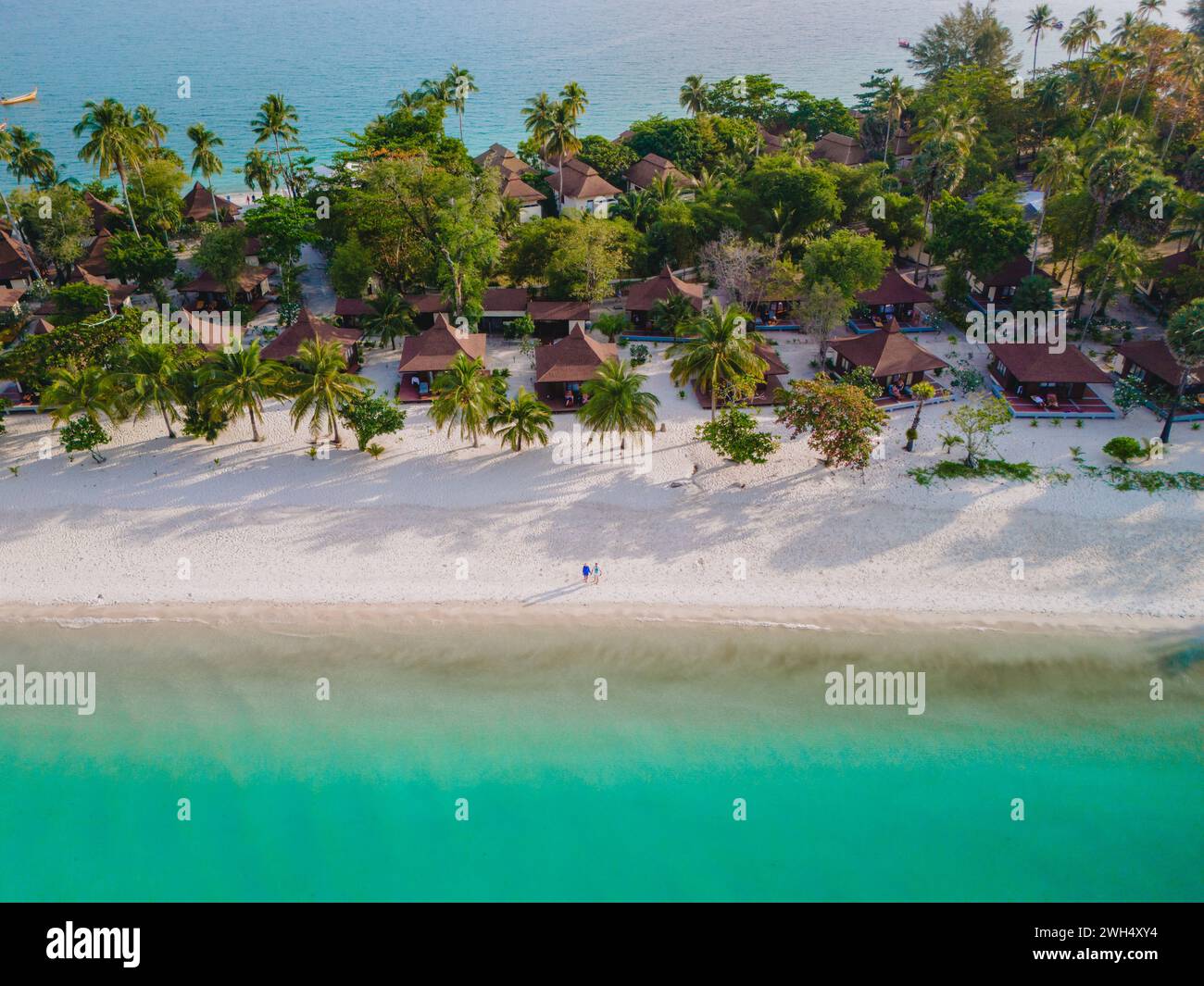 Drone view at a couple walking on the white sandy tropical beach of Koh ...
