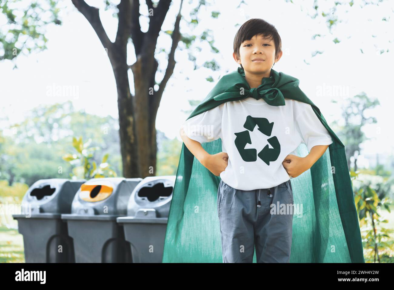 Cheerful young superhero boy with cape and recycle symbol promoting ...
