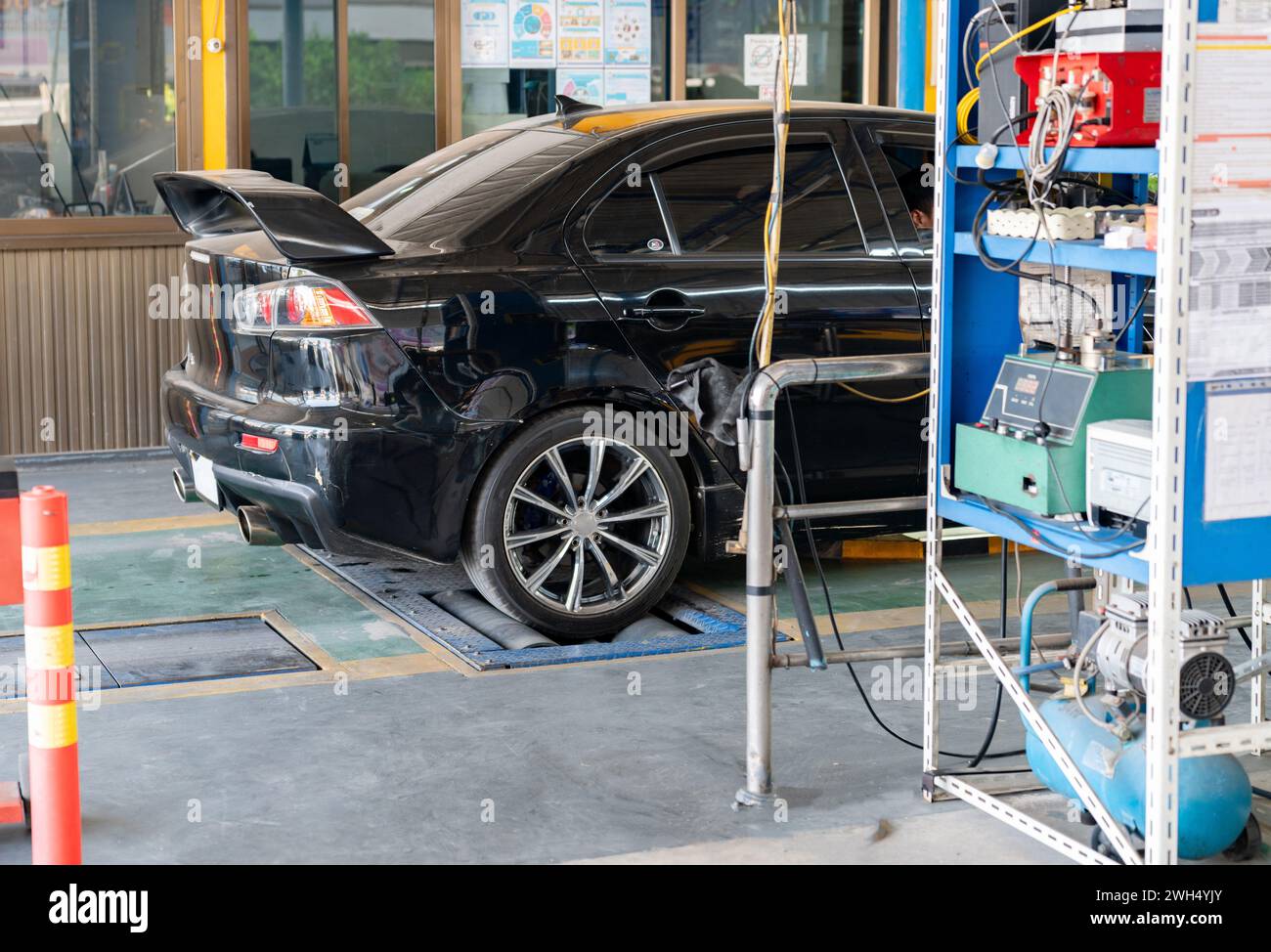 Rotating rear wheel on roller brake tester on inspection lane in car ...