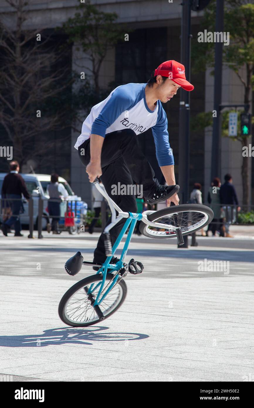 A Japanese BMX rider performs tricks on a public square in the middle ...