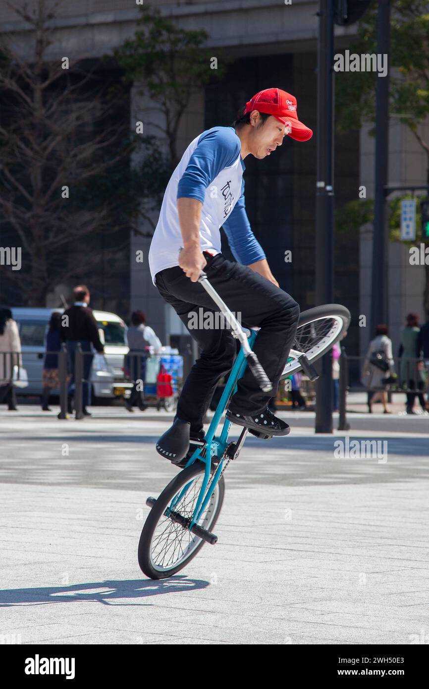 A Japanese BMX rider performs tricks on a public square in the middle ...