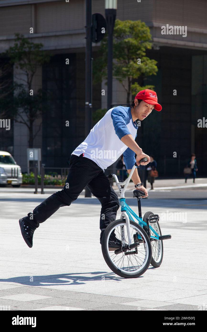 A Japanese BMX rider performs tricks on a public square in the middle ...