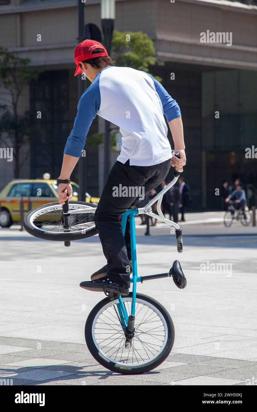 A Japanese BMX rider performs tricks on a public square in the middle ...
