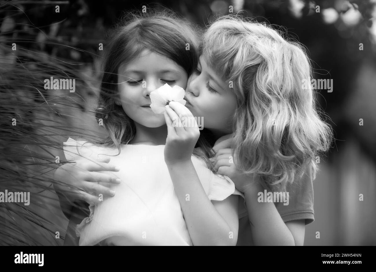 Two little children hug and kiss each other in summer garden. Kids couple in love. Romantic boy ...