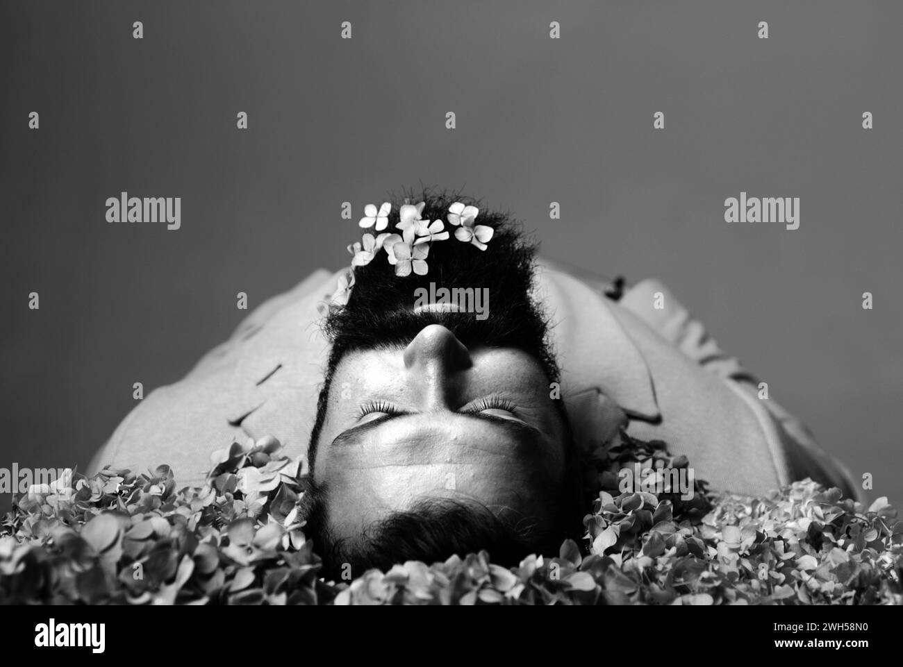 Man laying in flowers. Dead body. Bearded man with lay with closed eyes ...