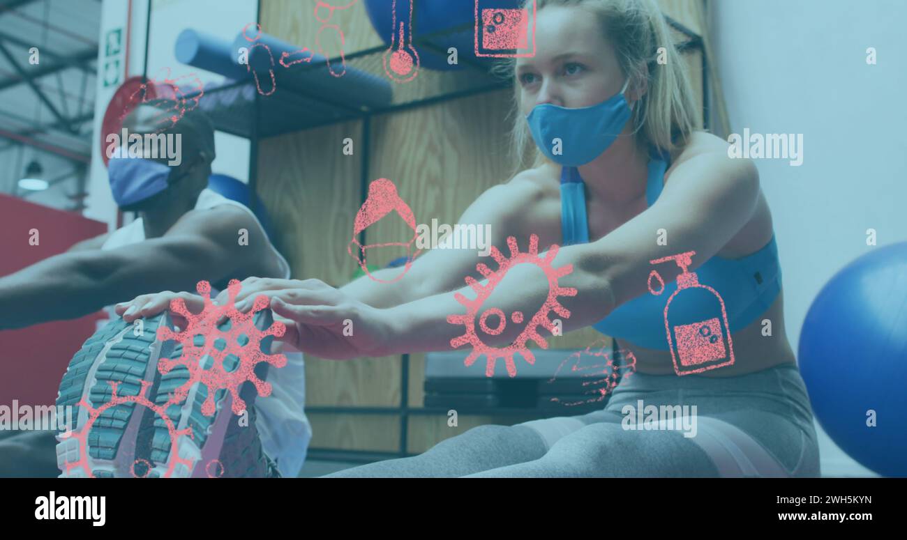 Image of covid-19 icons over diverse group wearing face masks working ...