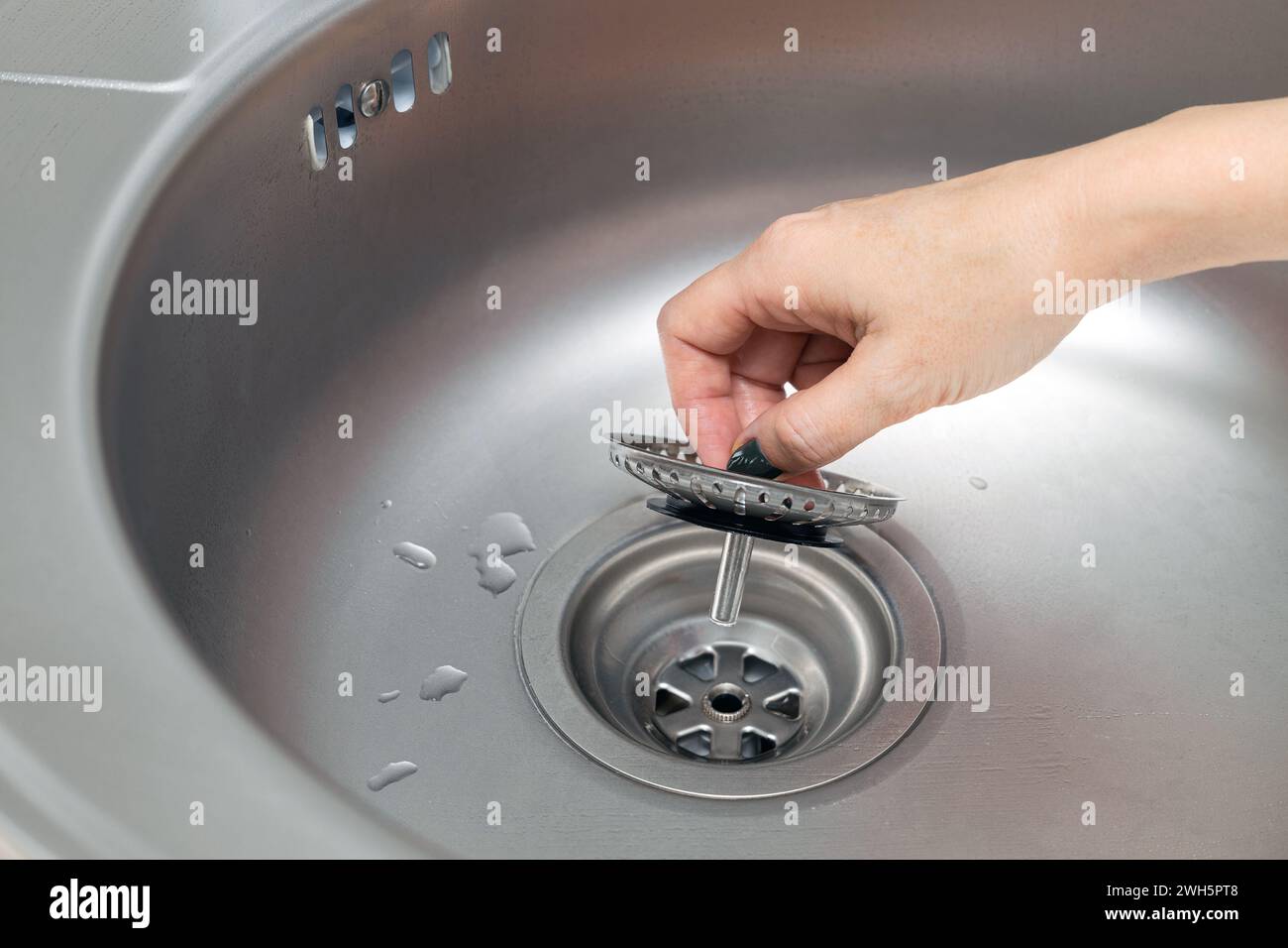 hand plugs the sink drain hole with a drain plug. High quality photo ...