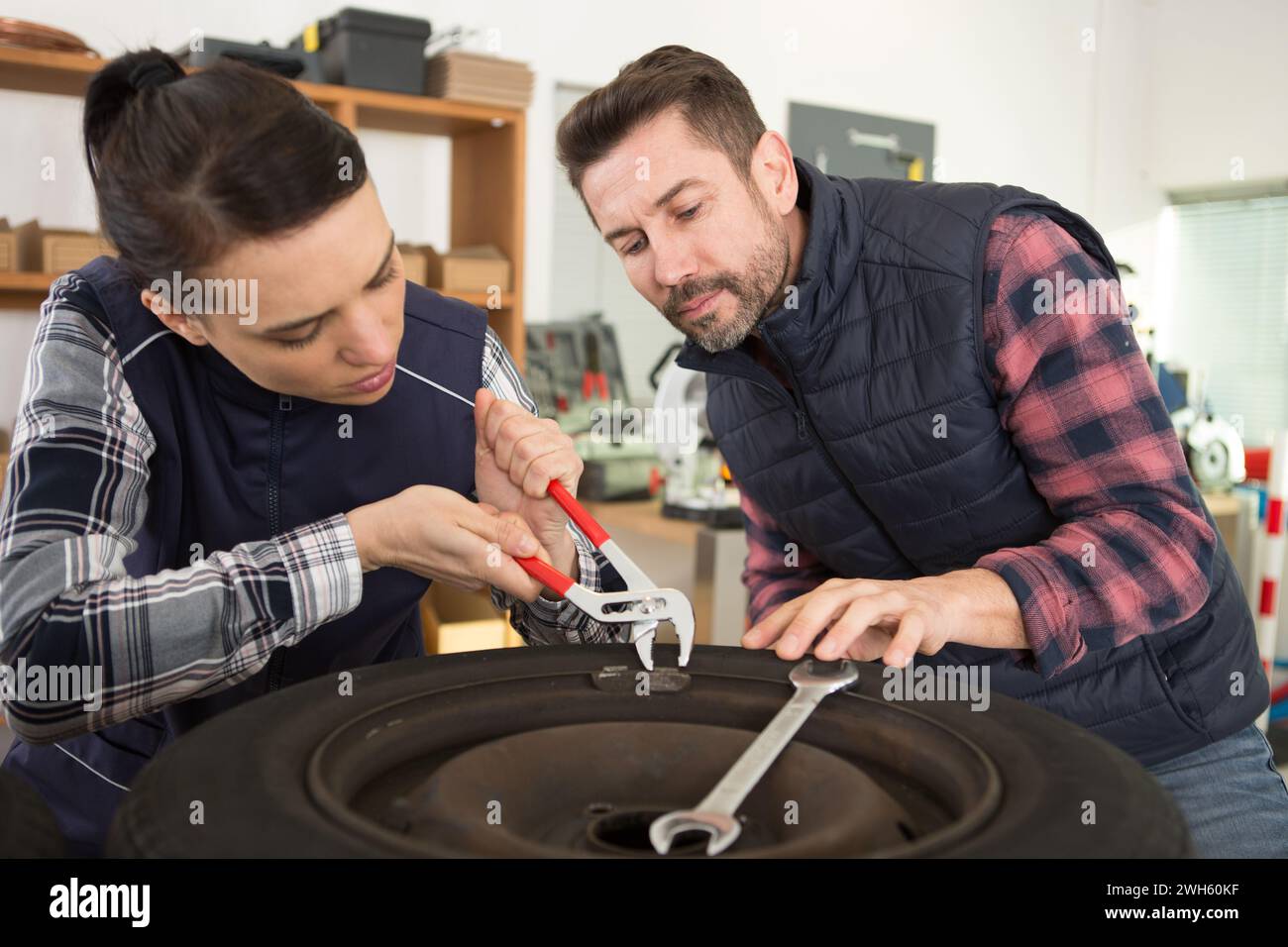 workers with spare wheel of a car in garage Stock Photo - Alamy