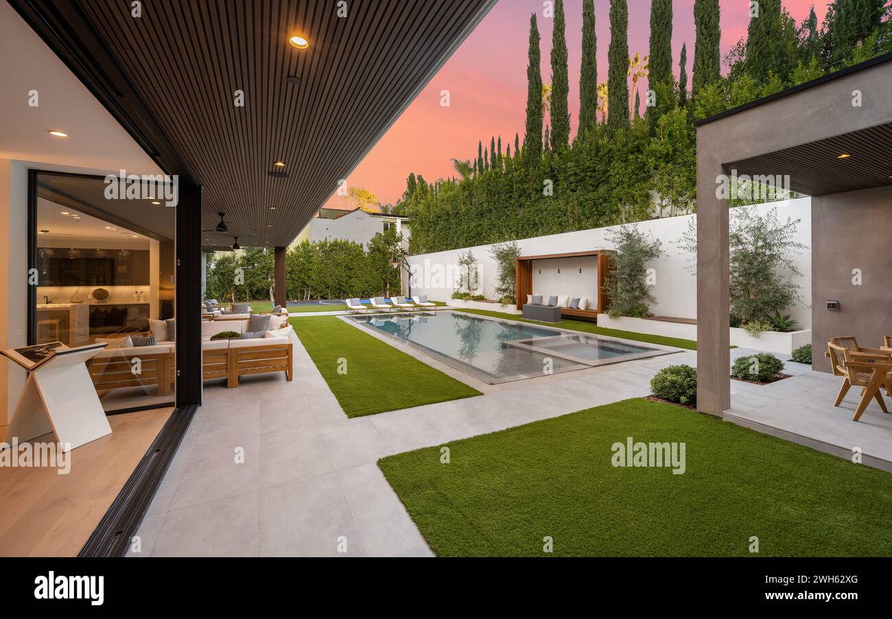 An outdoor patio adjacent to a sparkling pool in the backyard Stock ...