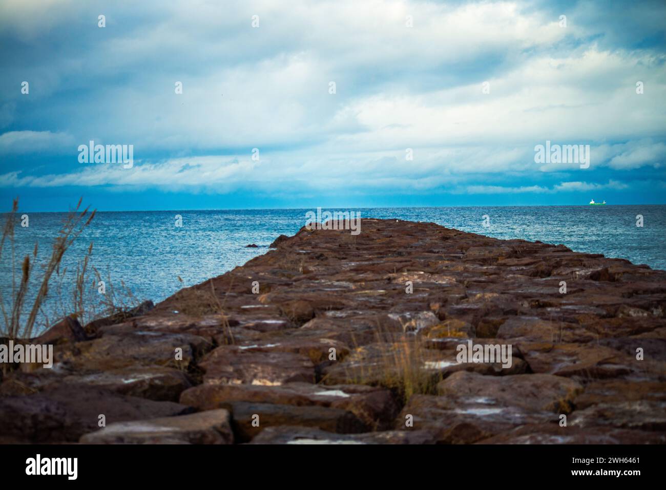 A picturesque coastal view with a stone dock gracefully extending into ...