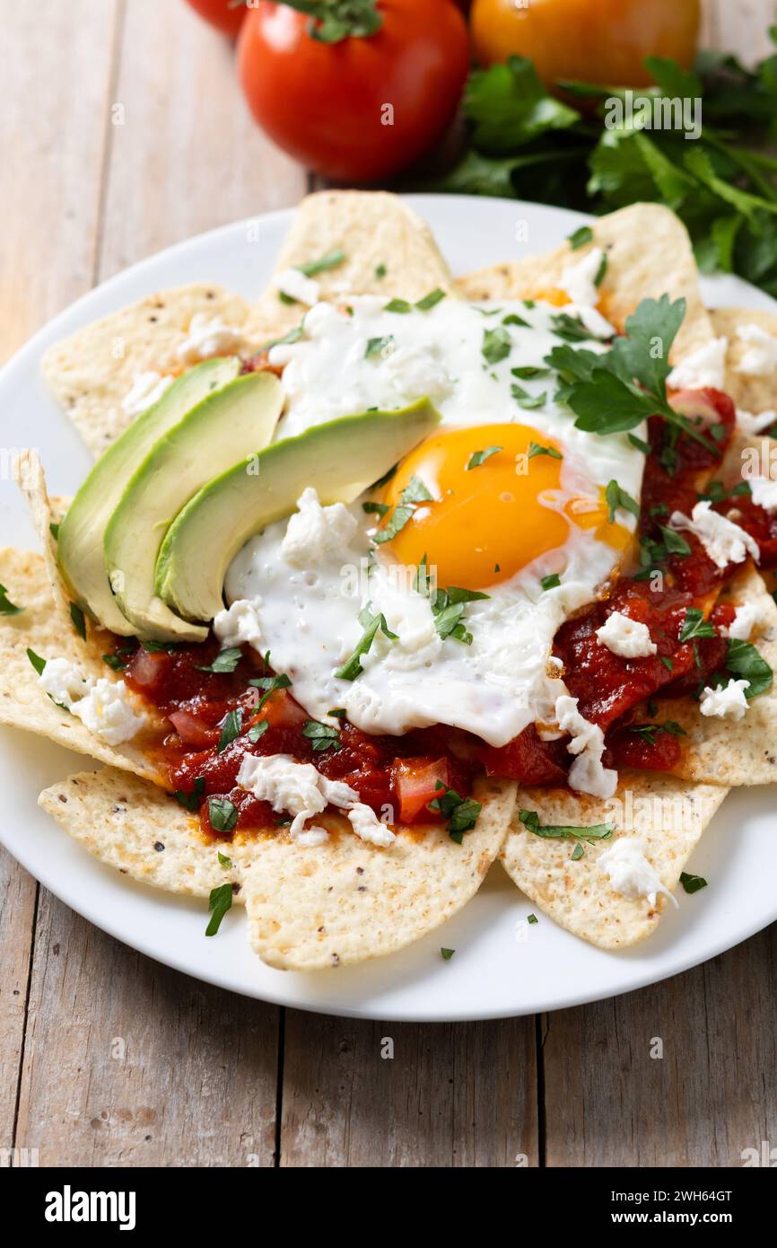 Traditional Mexican chilaquiles breakfast on wooden table Stock Photo ...