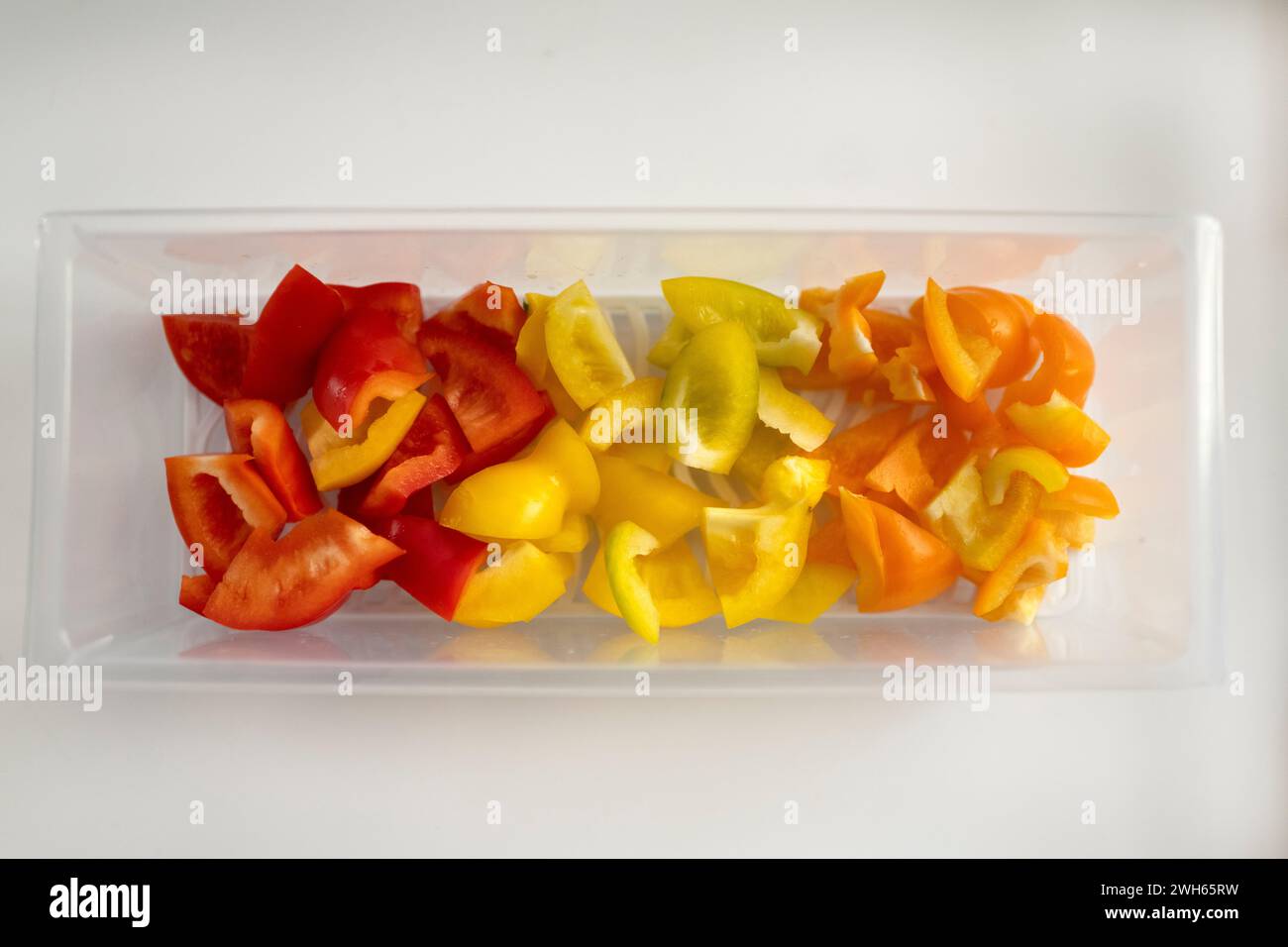 A top view of chunks of red, yellow, and orange peppers in a clear ...