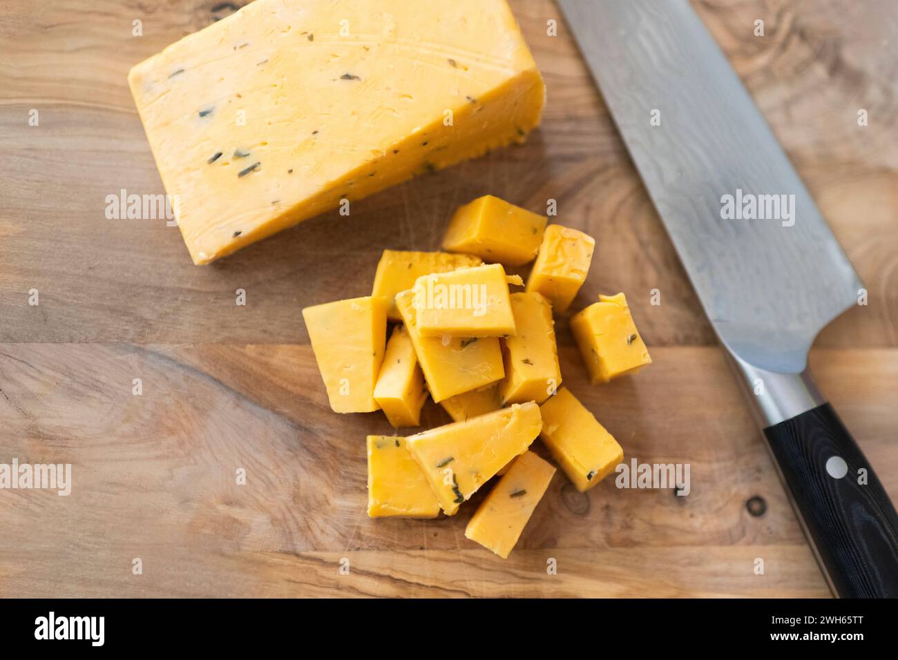 A top view of a knife resting on a wooden cutting board with chunks of ...