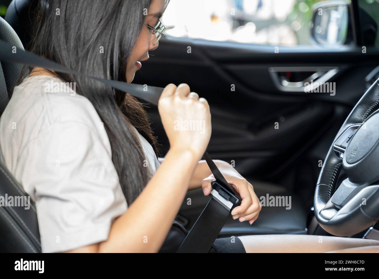 Close up of hand woman pulling seat belt in her car; Car safety concept ...