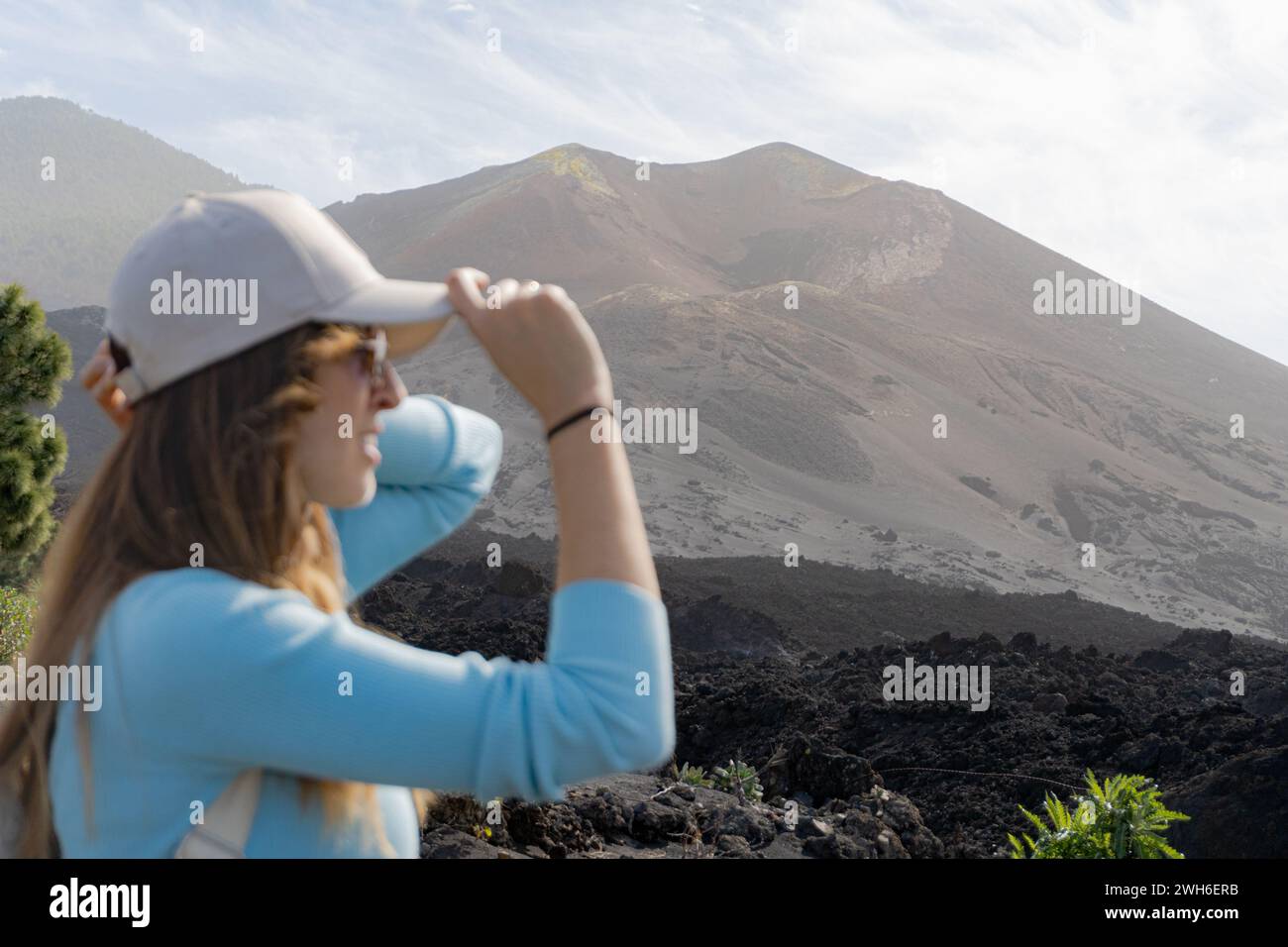 woman with glasses puts on her cap in front of the tajogaite volcano ...