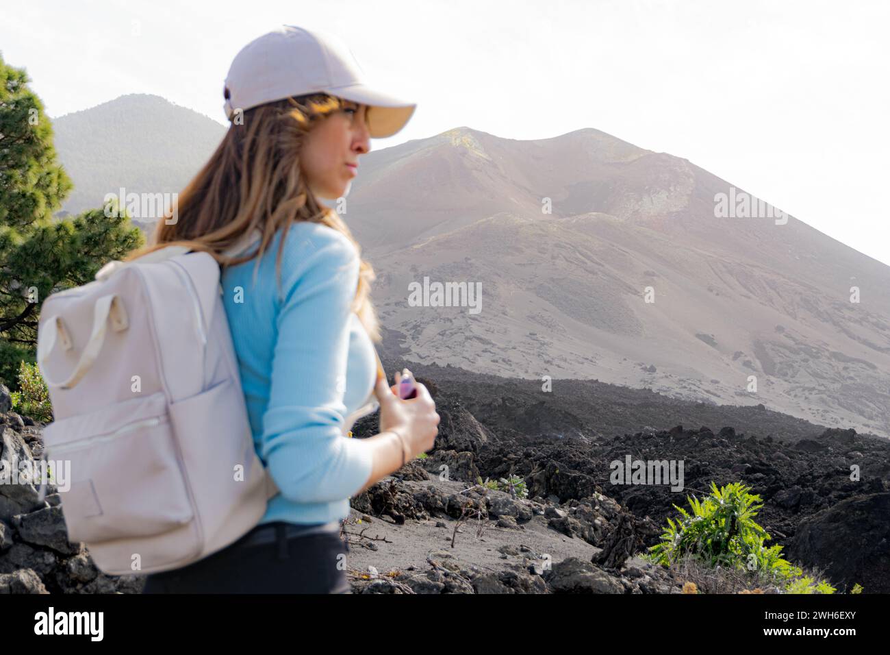 backpacker woman with cap looks towards the Tajogaite volcano Stock ...