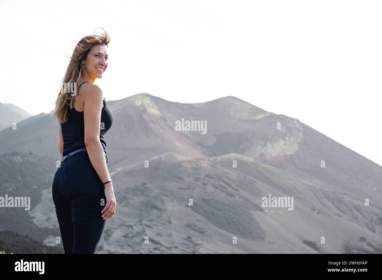 standing woman smiles from the viewpoint of a volcano in La Palma Stock ...
