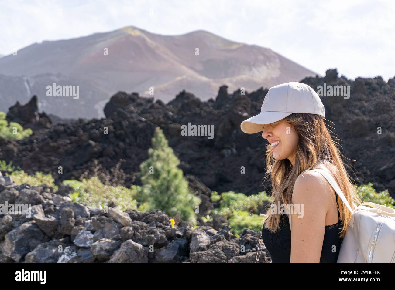 close-up woman walks smiling looking down in front of a volcano Stock ...