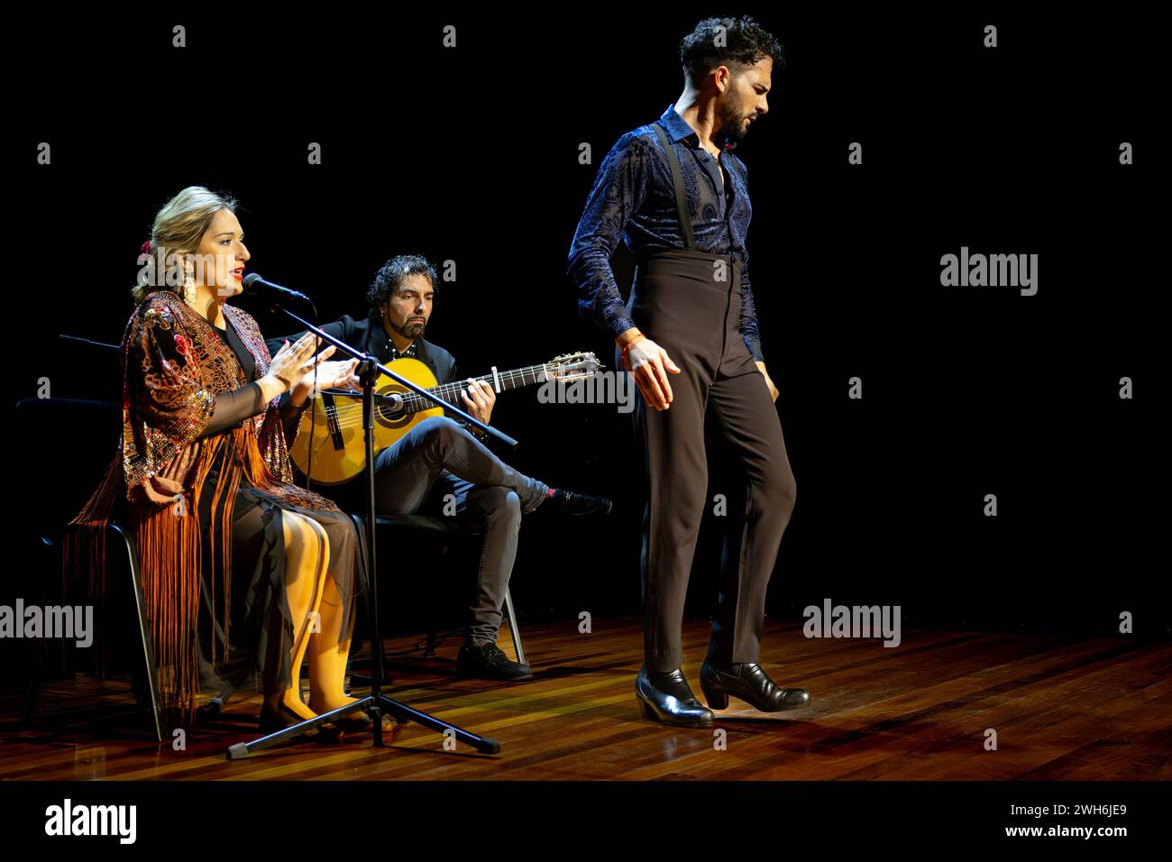 "Flamenco artist dancing passionately on stage, with singers and ...