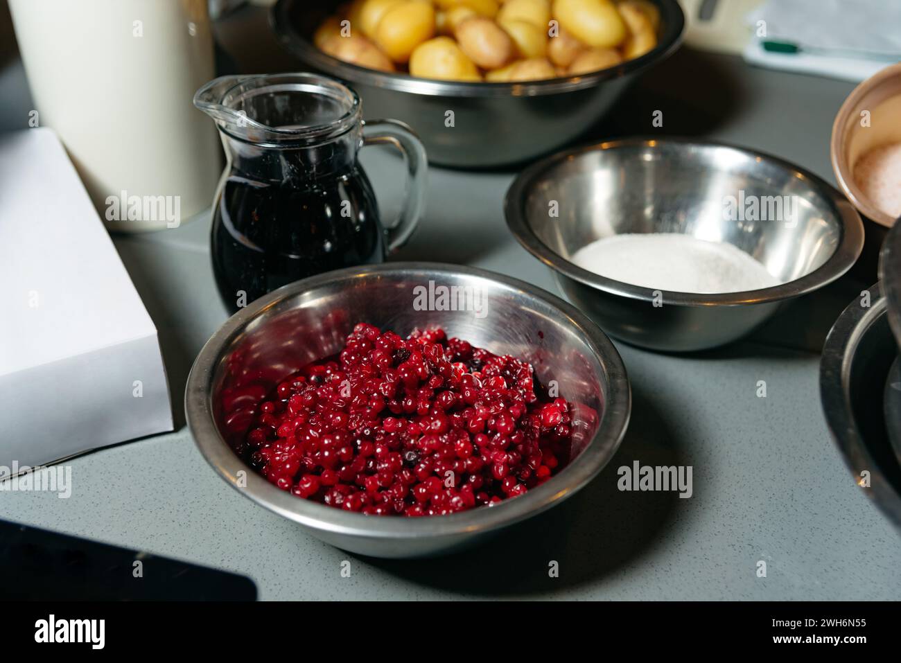 A stainless steel bowl filled with vibrant red currants on a kitchen ...