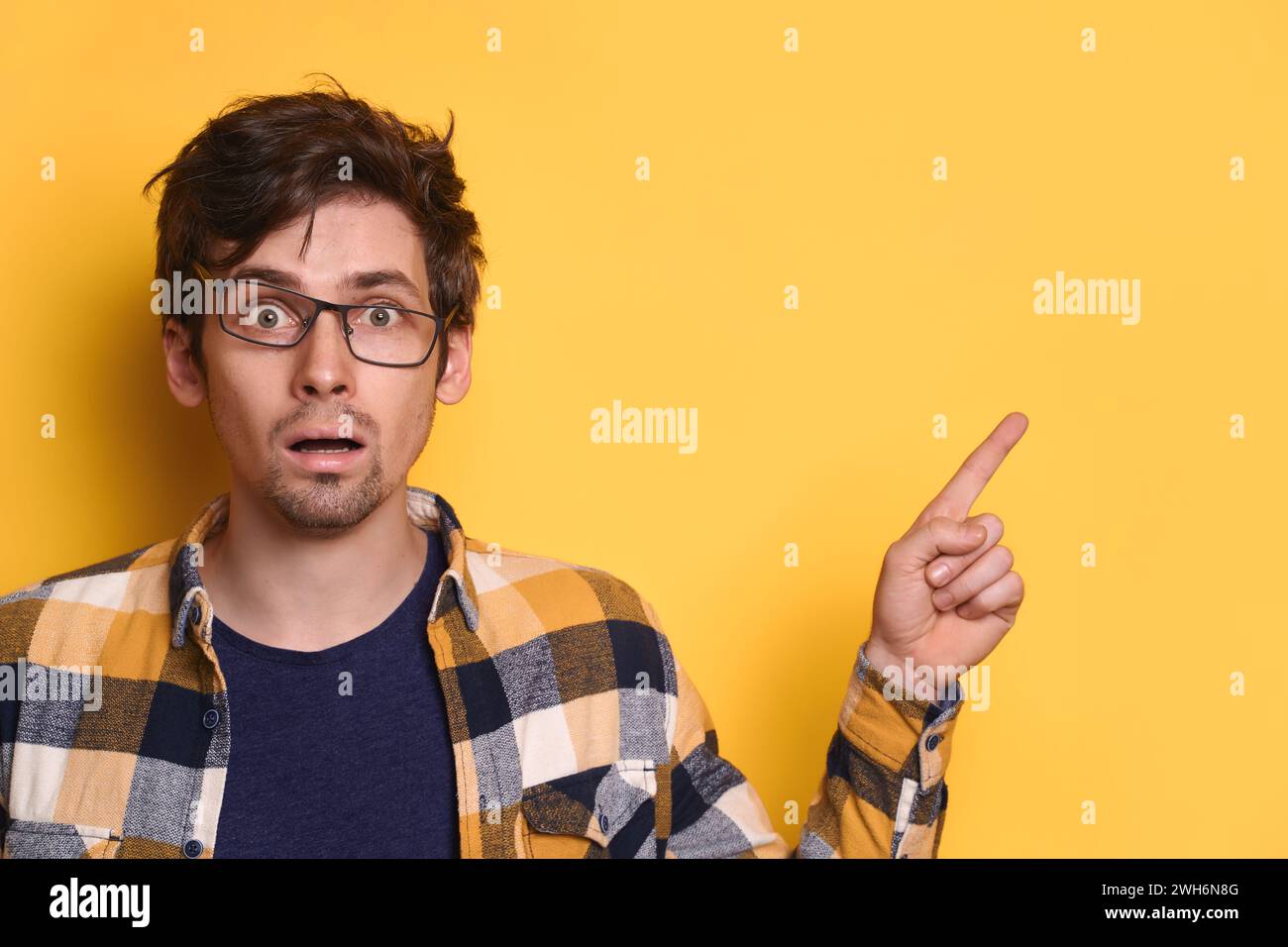 Portrait of confused man in glasses and casual shirt pointing on ...