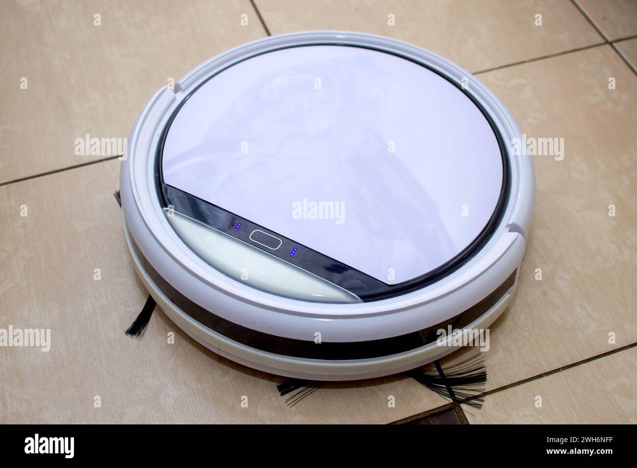 Robot vacuum cleaner working in the kitchen, sweeping debris from the ...
